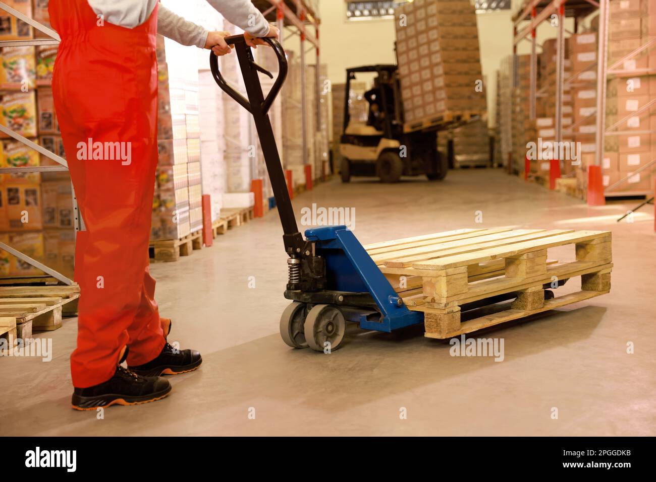 Worker moving wooden pallets with manual forklift in warehouse, closeup ...