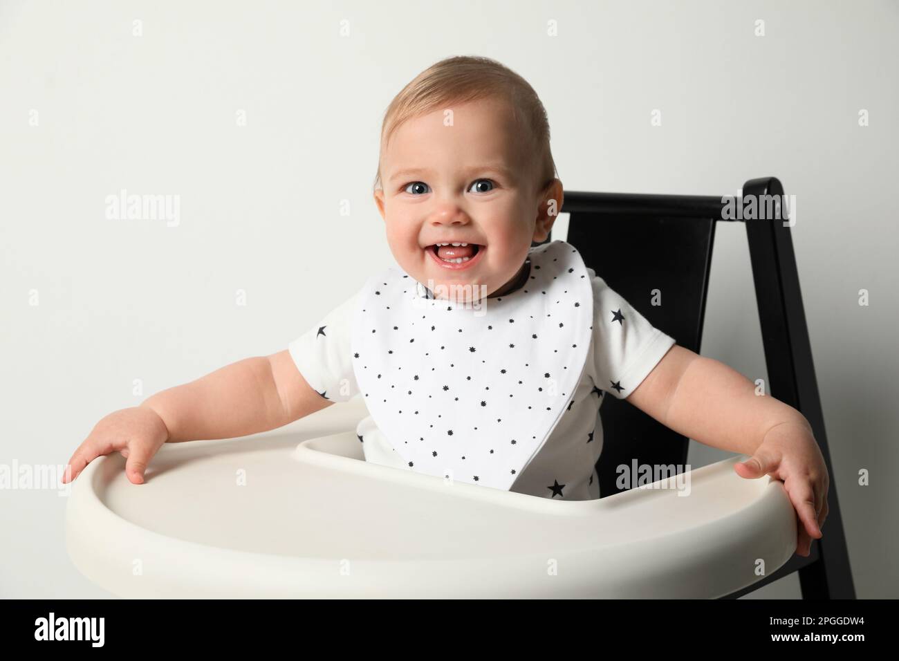 Cute little baby wearing bib in highchair on white background Stock ...