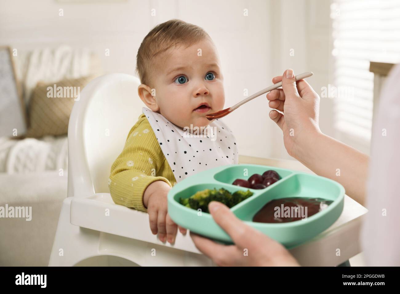 Mother feeding her little baby at home. Kid wearing bib Stock Photo - Alamy