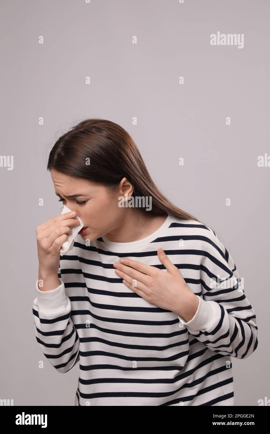 Woman blowing nose on light grey background. Cold symptoms Stock Photo ...