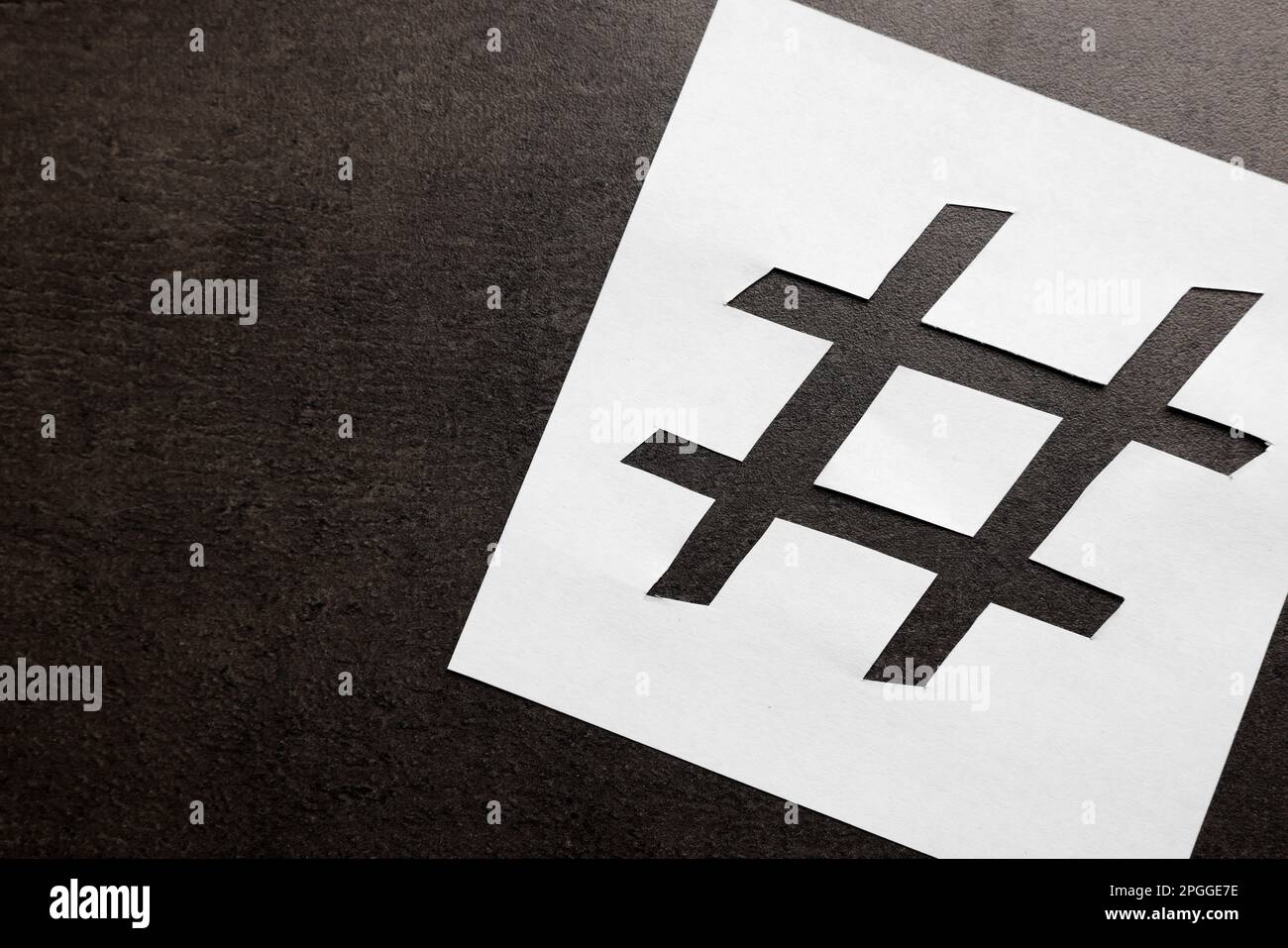White paper stencil with symbol of hashtag on dark background, top view ...