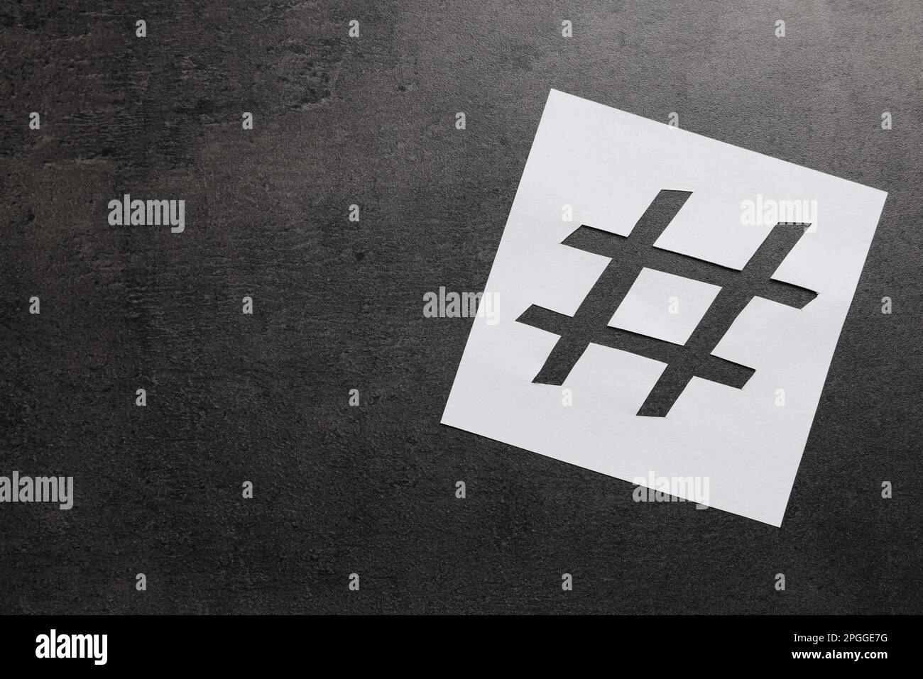 White paper stencil with symbol of hashtag on dark background, top view ...