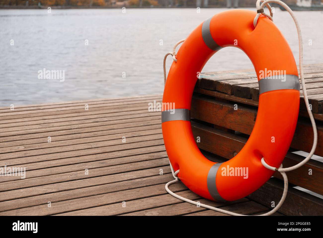 Orange lifebuoy on wooden pier near water. Rescue equipment Stock Photo ...