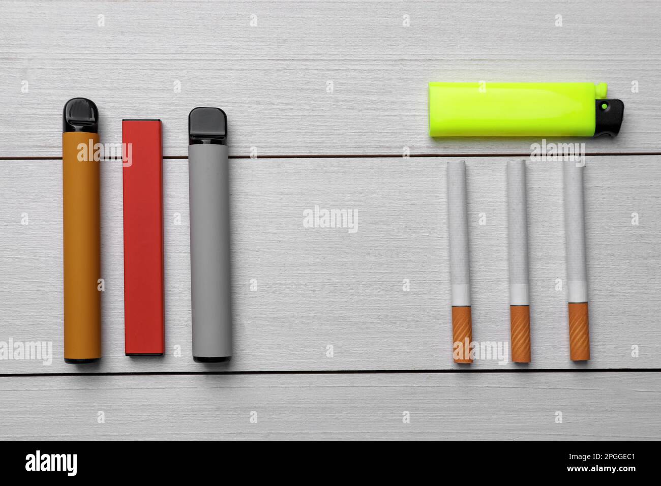 Lighter, electronic and regular cigarettes on white wooden background ...