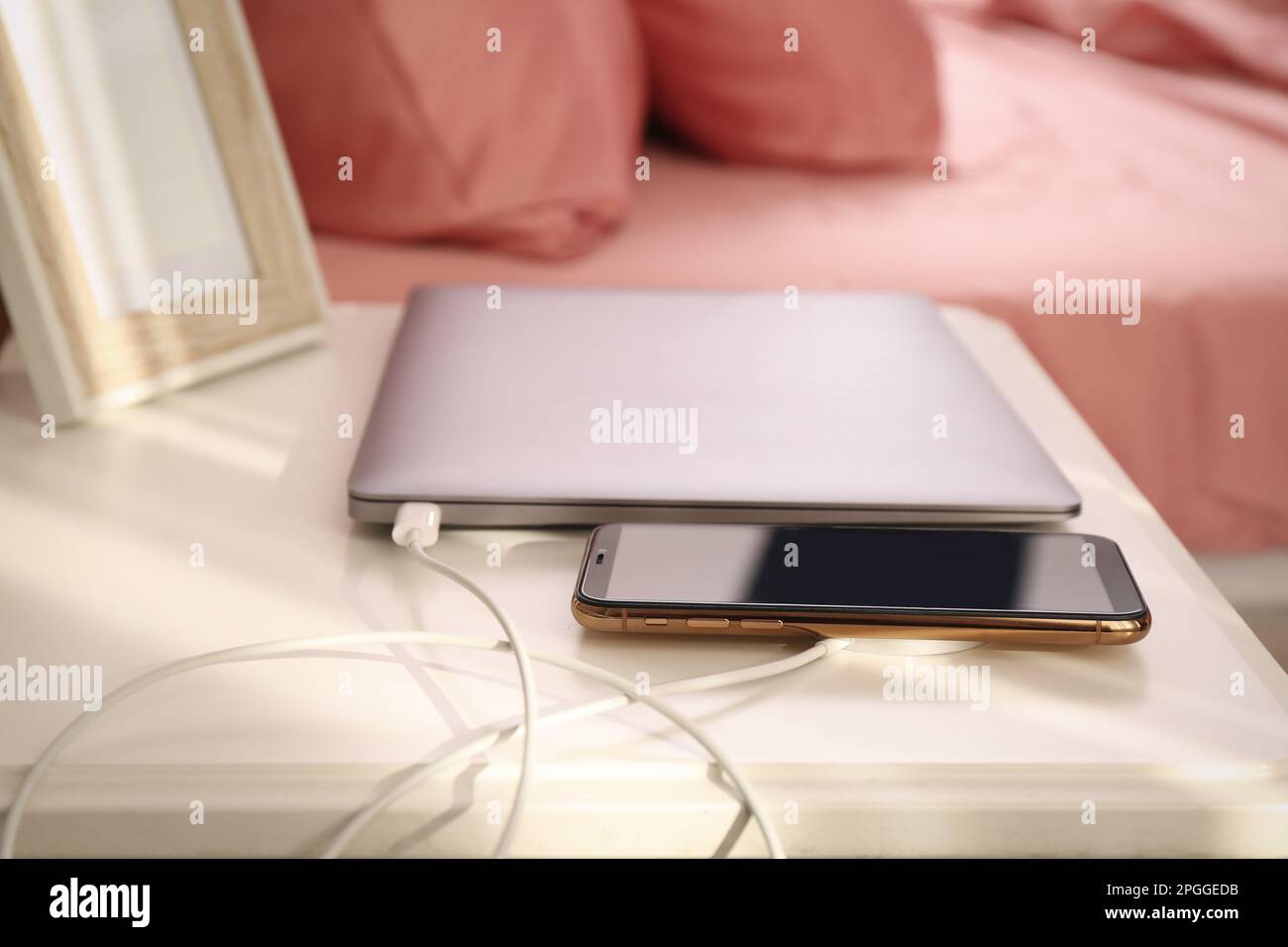 Smartphone with wireless charger connected to laptop on white table in ...