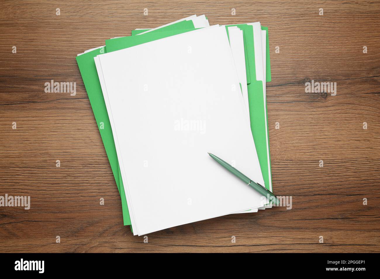 Light green files with blank sheets of paper and pen on wooden table ...