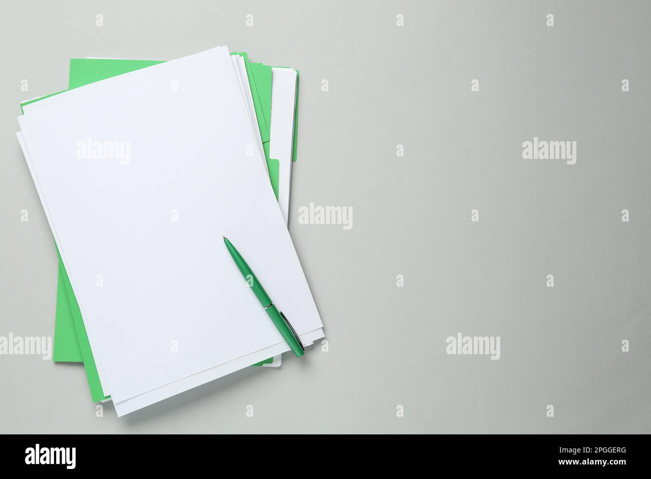 Green files with blank sheets of paper and pen on light grey background ...