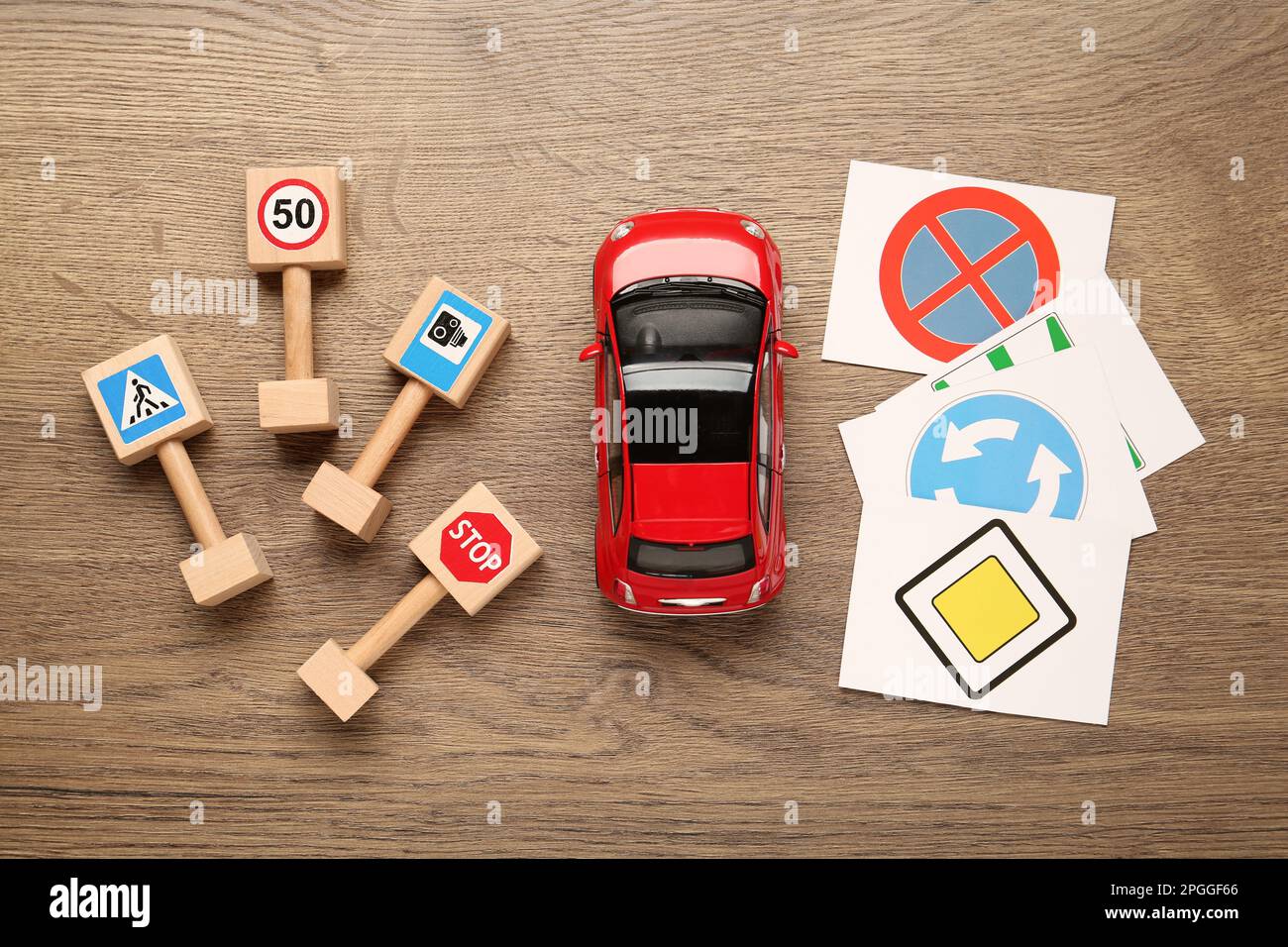 Many different road signs and toy car on wooden background, flat lay ...