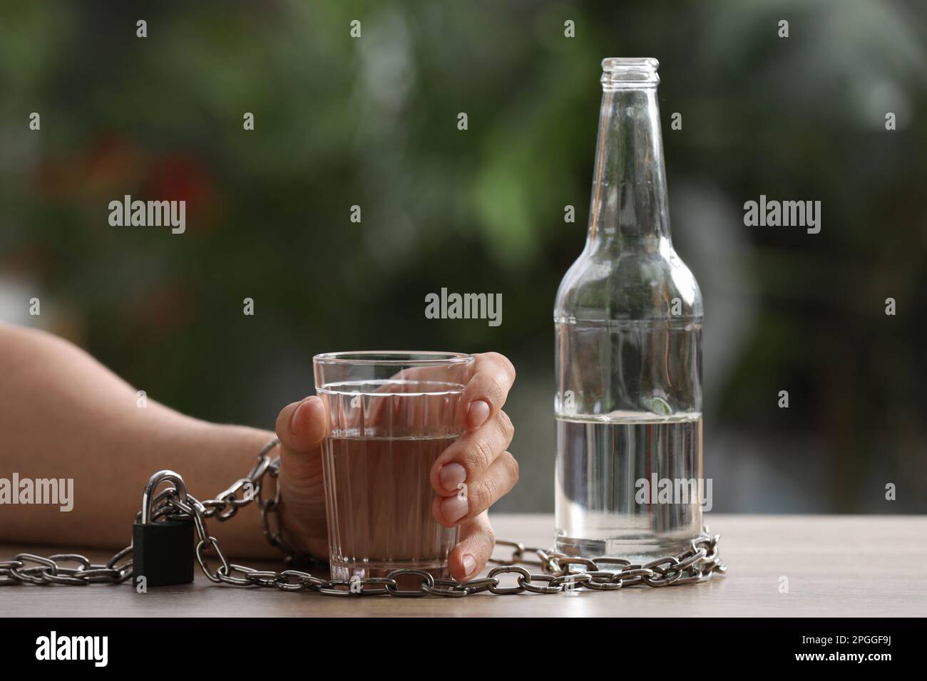 Man chained to glass of vodka at table against blurred background ...