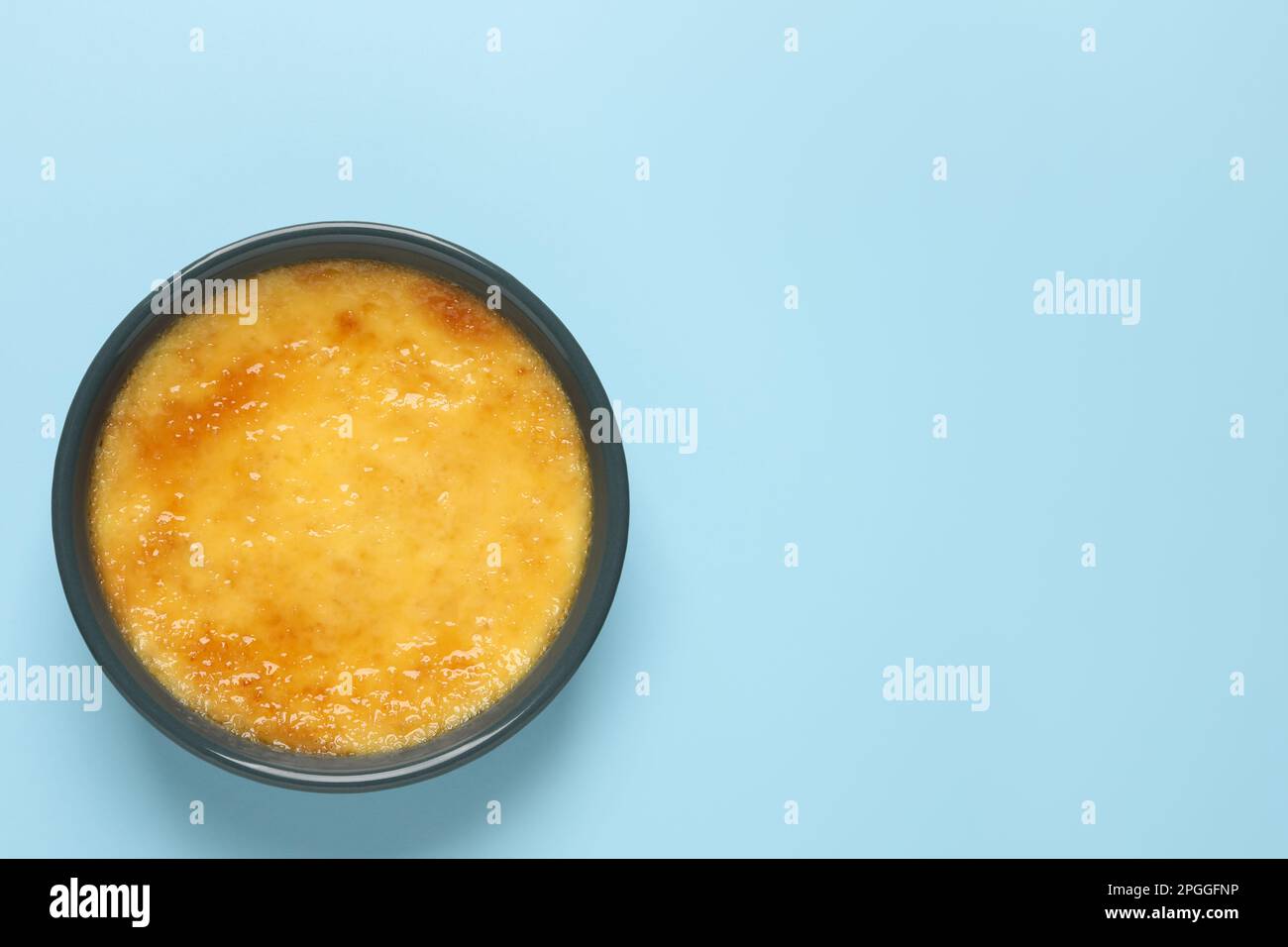 Delicious creme brulee in ceramic ramekin on light blue background, top ...