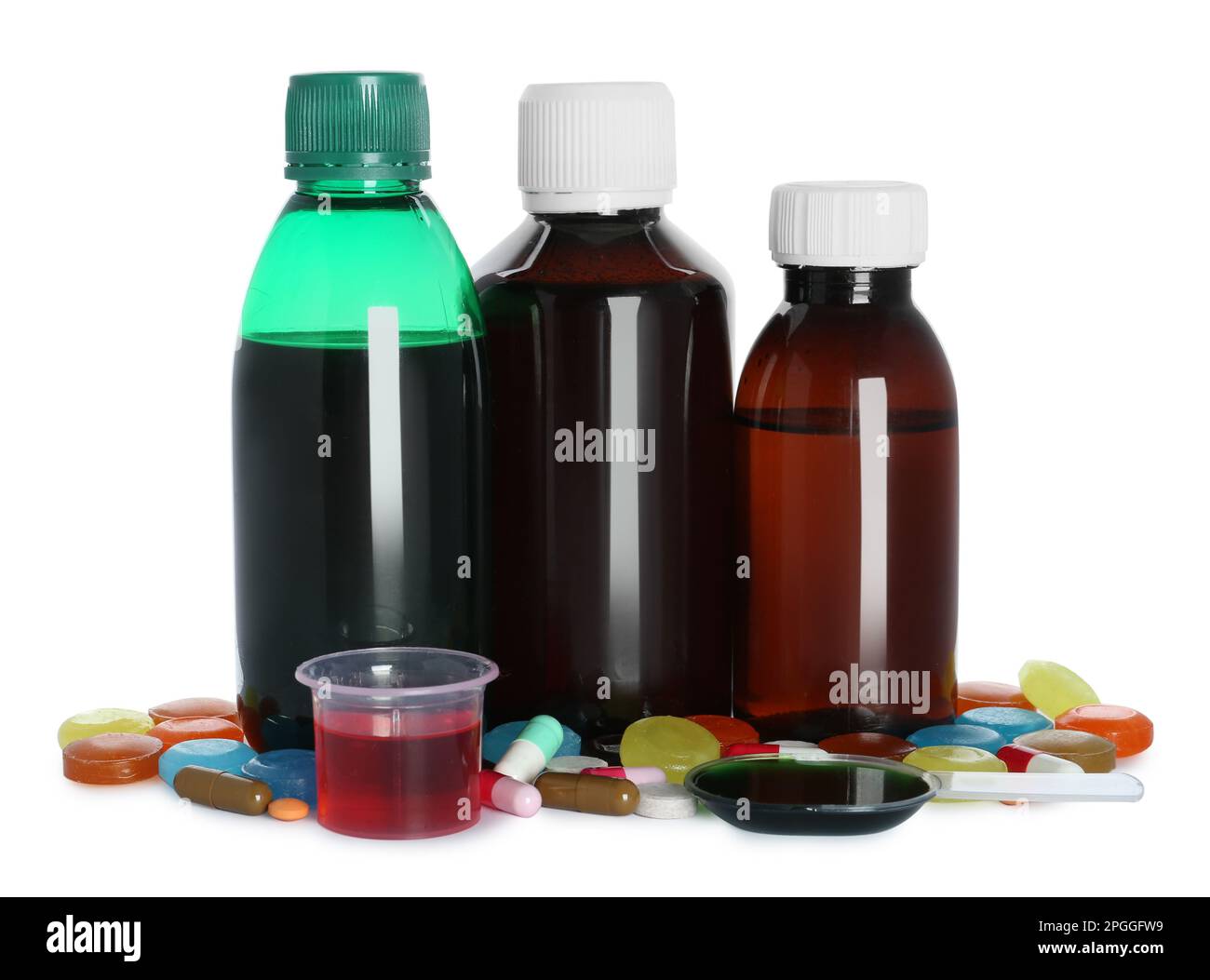 Bottles of cough syrup, dosing spoon, measuring cup and pills on white ...
