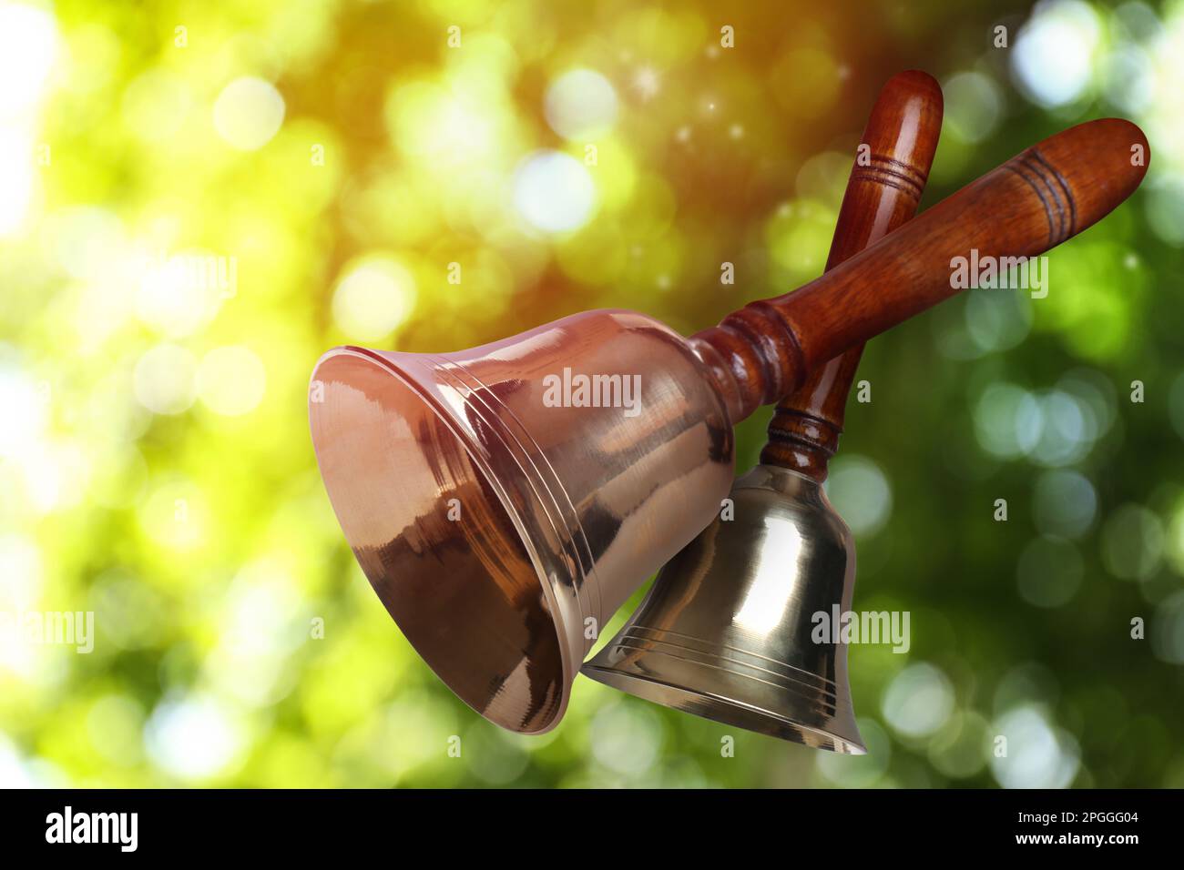 Shiny school bells with wooden handle outdoors. Bokeh effect Stock ...