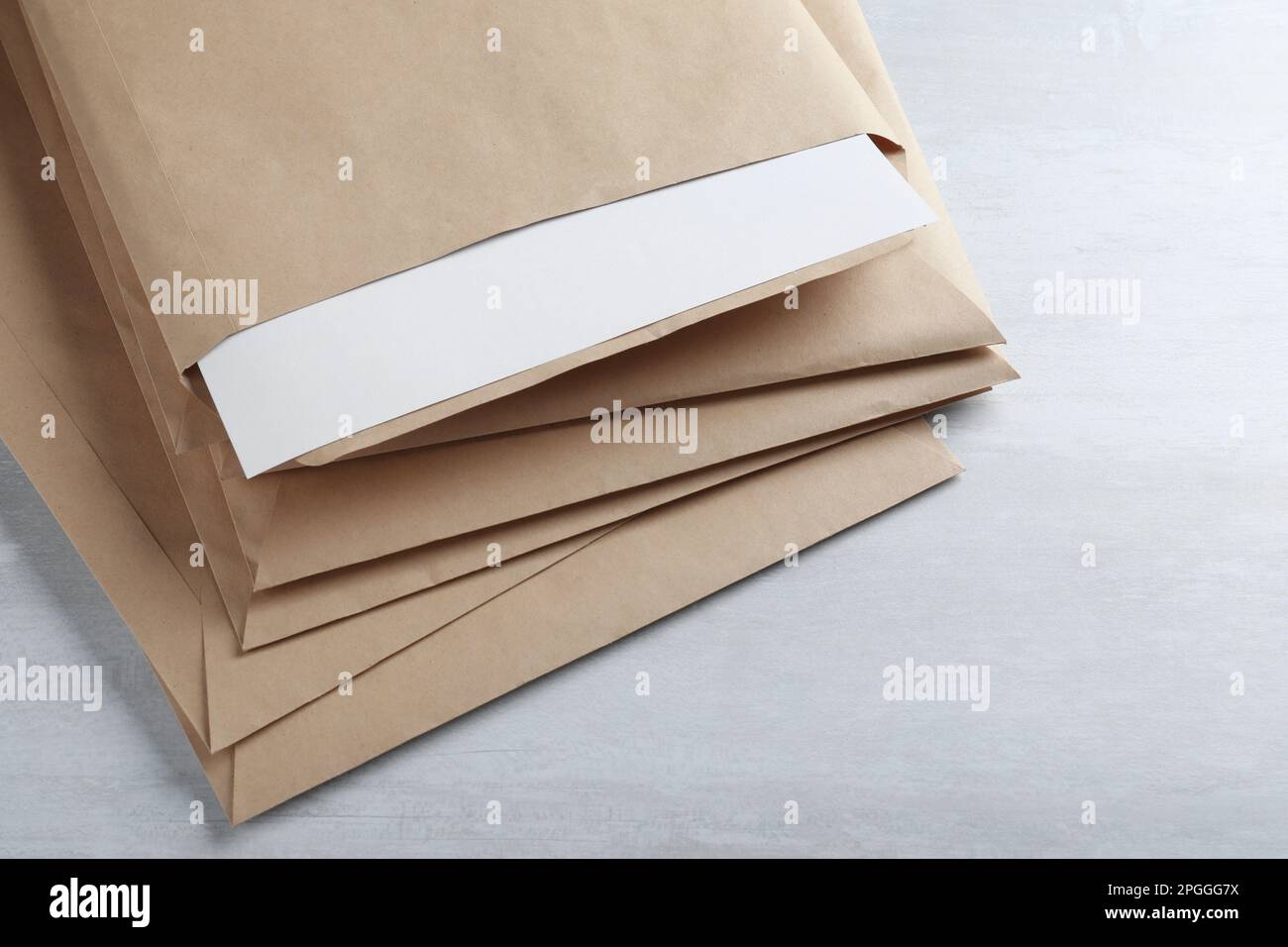 Stack of big kraft paper envelopes on light table, closeup Stock Photo ...