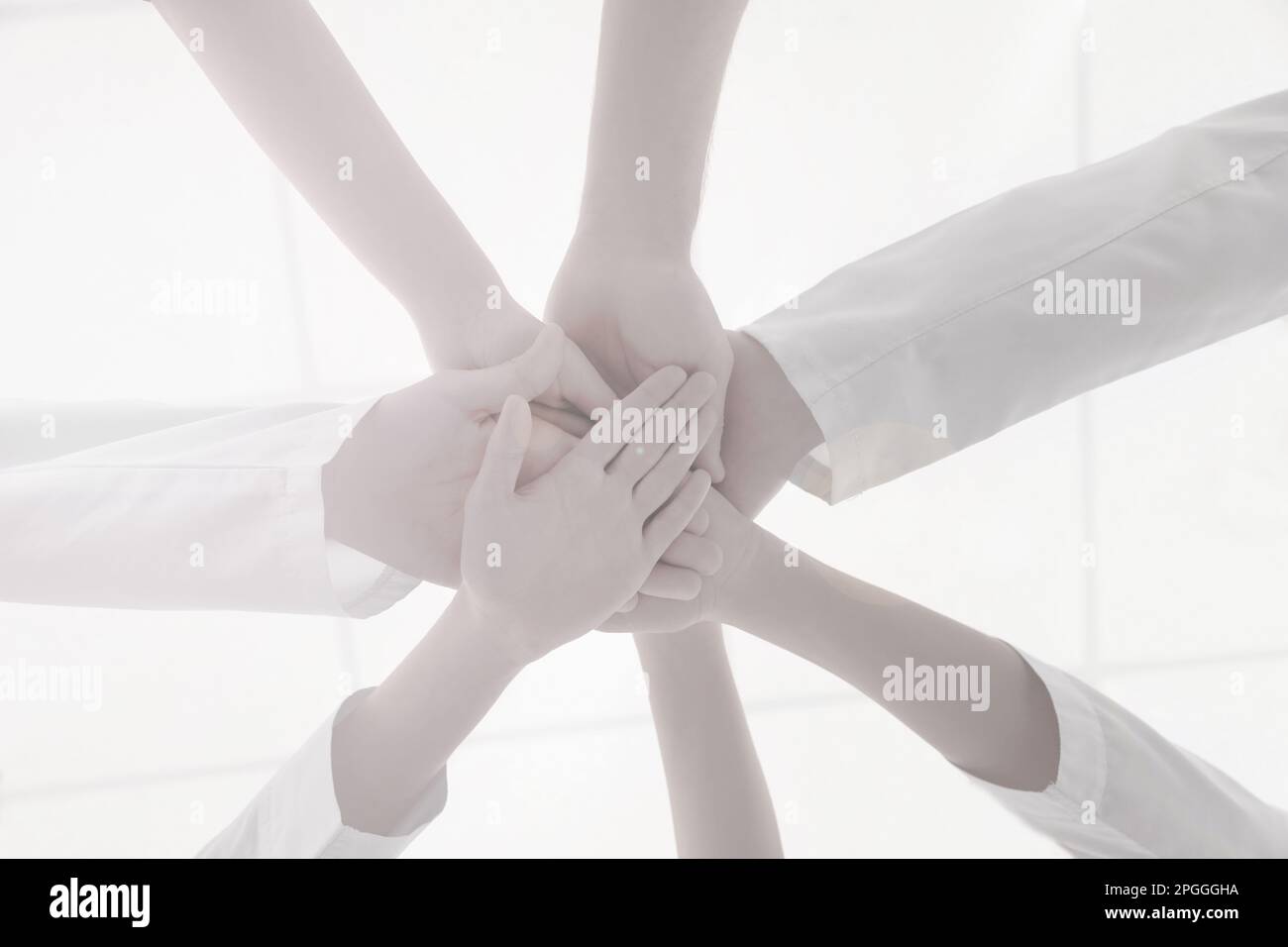 Team of medical workers holding hands together on light background ...