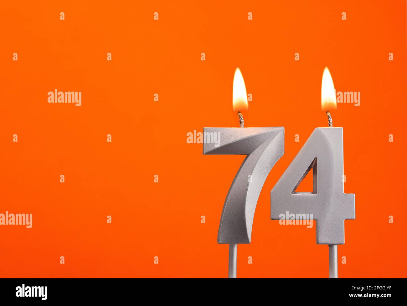 Candle number 74 - Birthday in orange background Stock Photo - Alamy