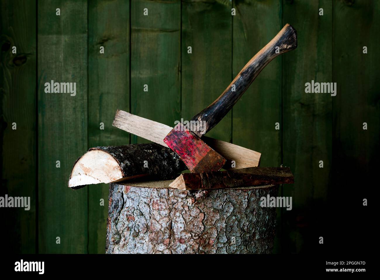 Axe on chopping block with log in front of green wooden wall, studio ...