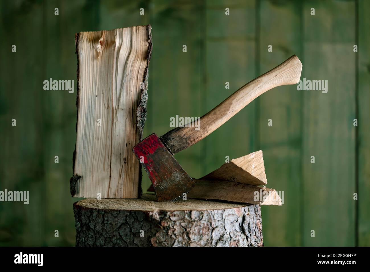Axe on chopping block with log in front of green wooden wall, studio ...