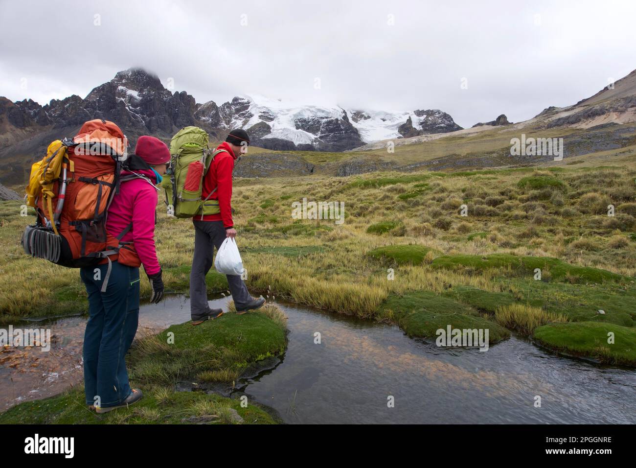 A mountain climber couple cross river in Peru in the Andes while on a ...