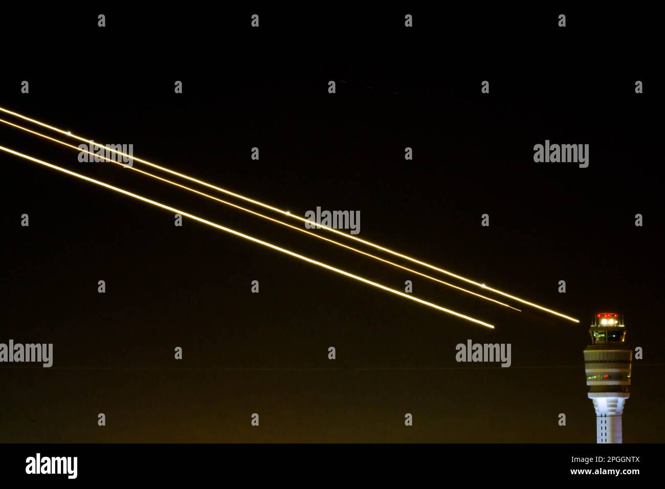 Airport with control tower and unfocused lights of airplane taking off ...