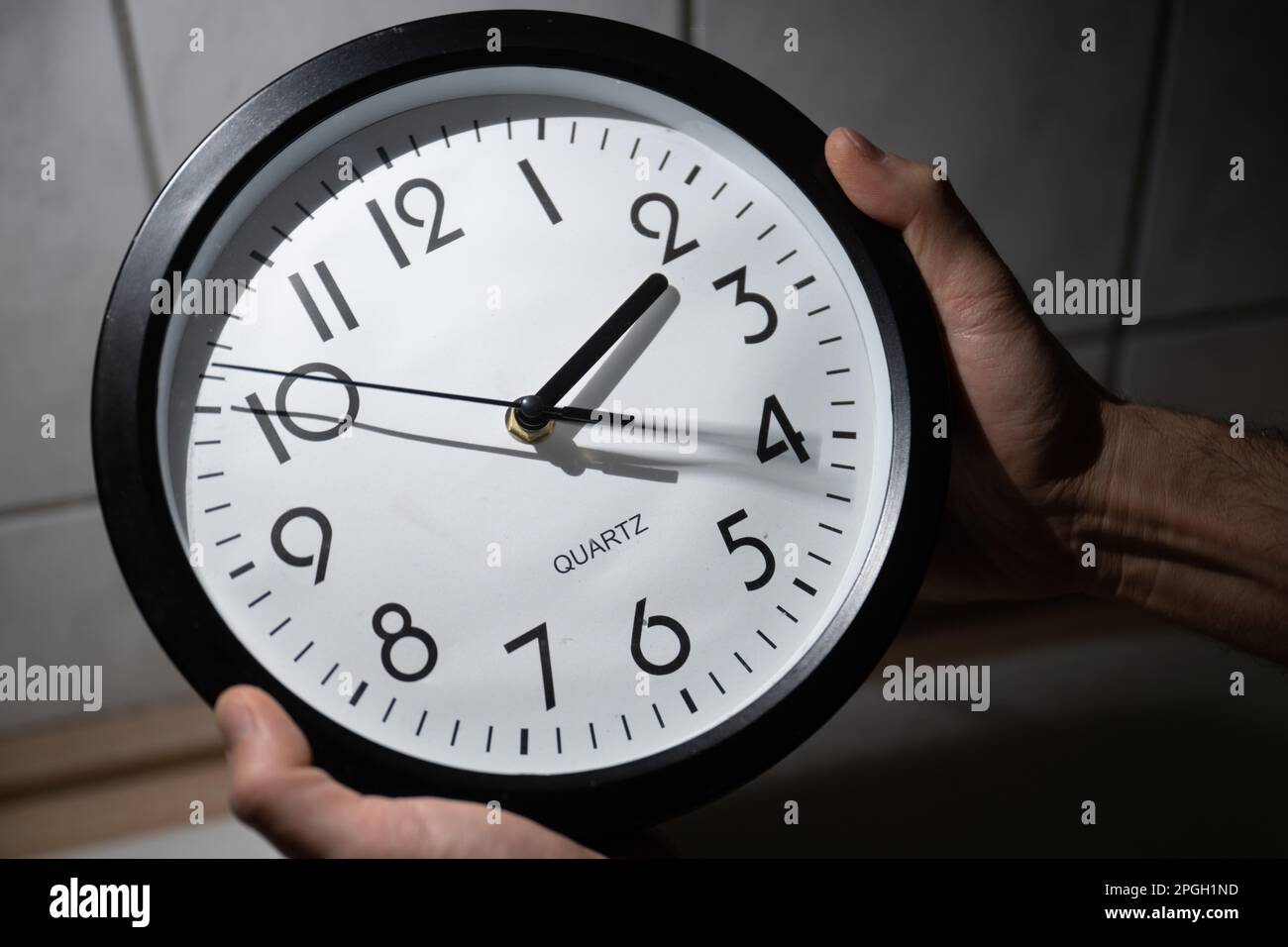 21 March 2023, Hesse, Gießen: A man sets an analog clock forward from ...