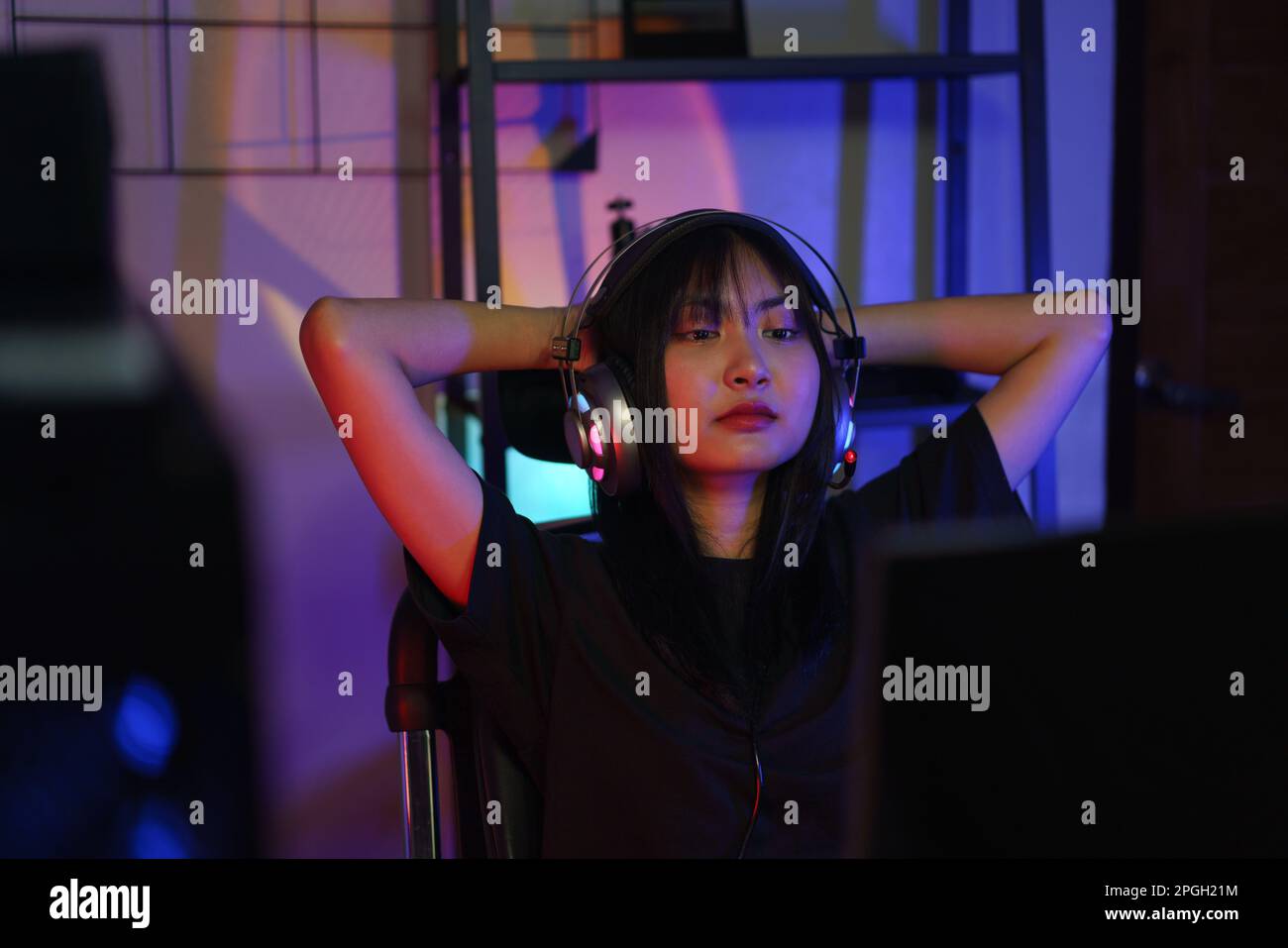 Female cyber hacker gamer holds hands behind head to resting after ...