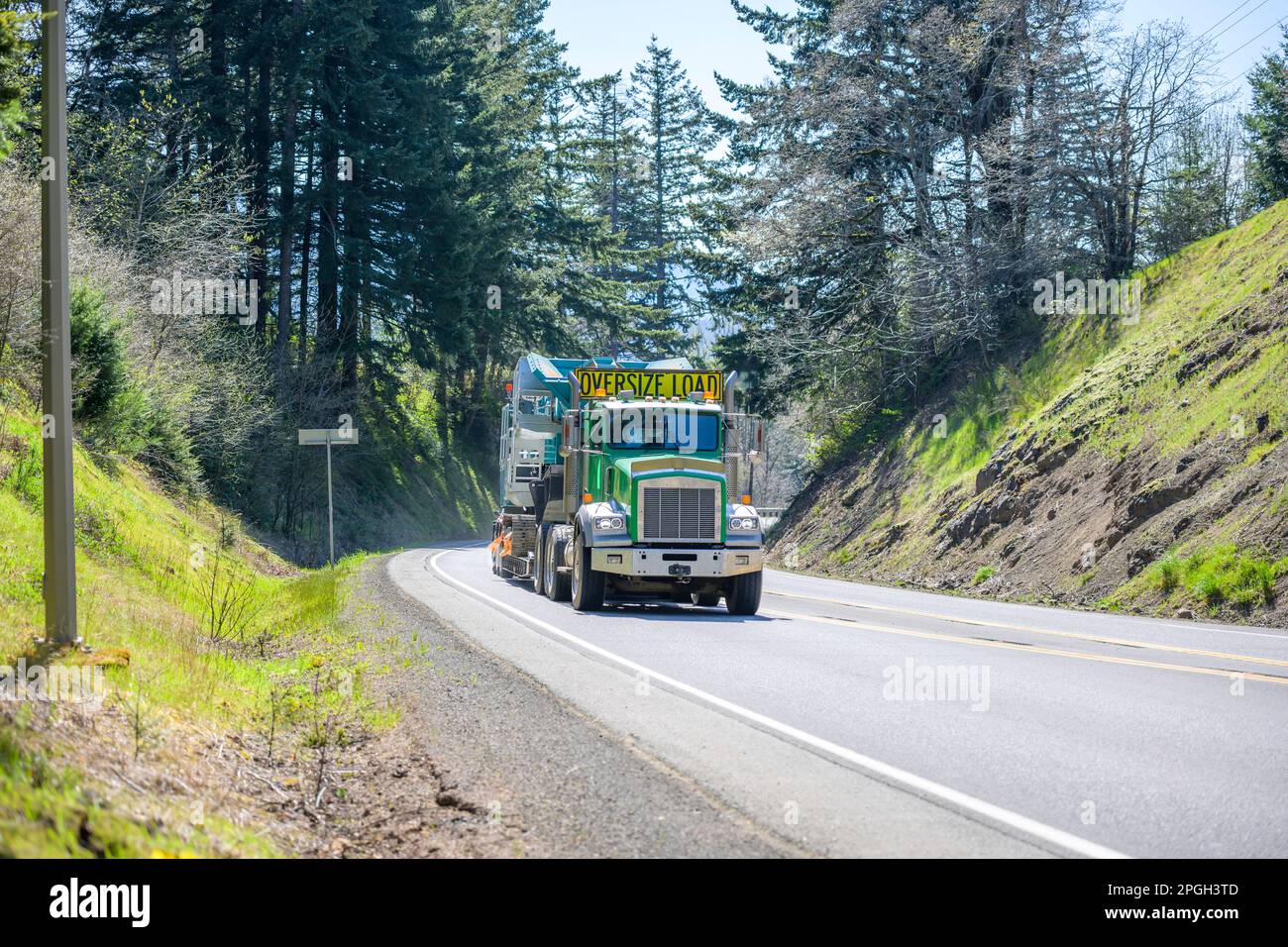Big rig classic green semi truck tractor with oversize load sign on the ...
