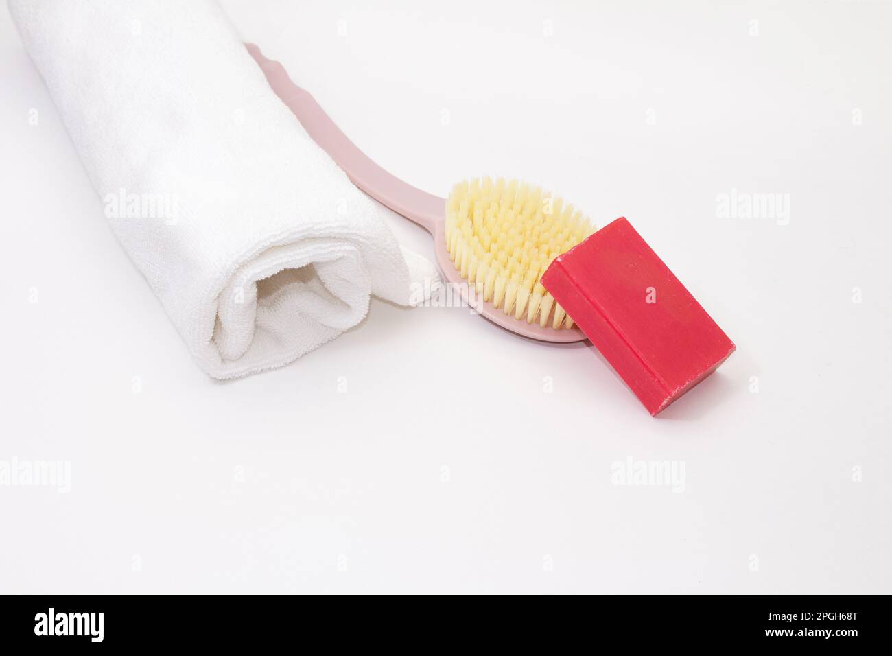 Rolled up towel with wash brush and pink soap on white isolated ...