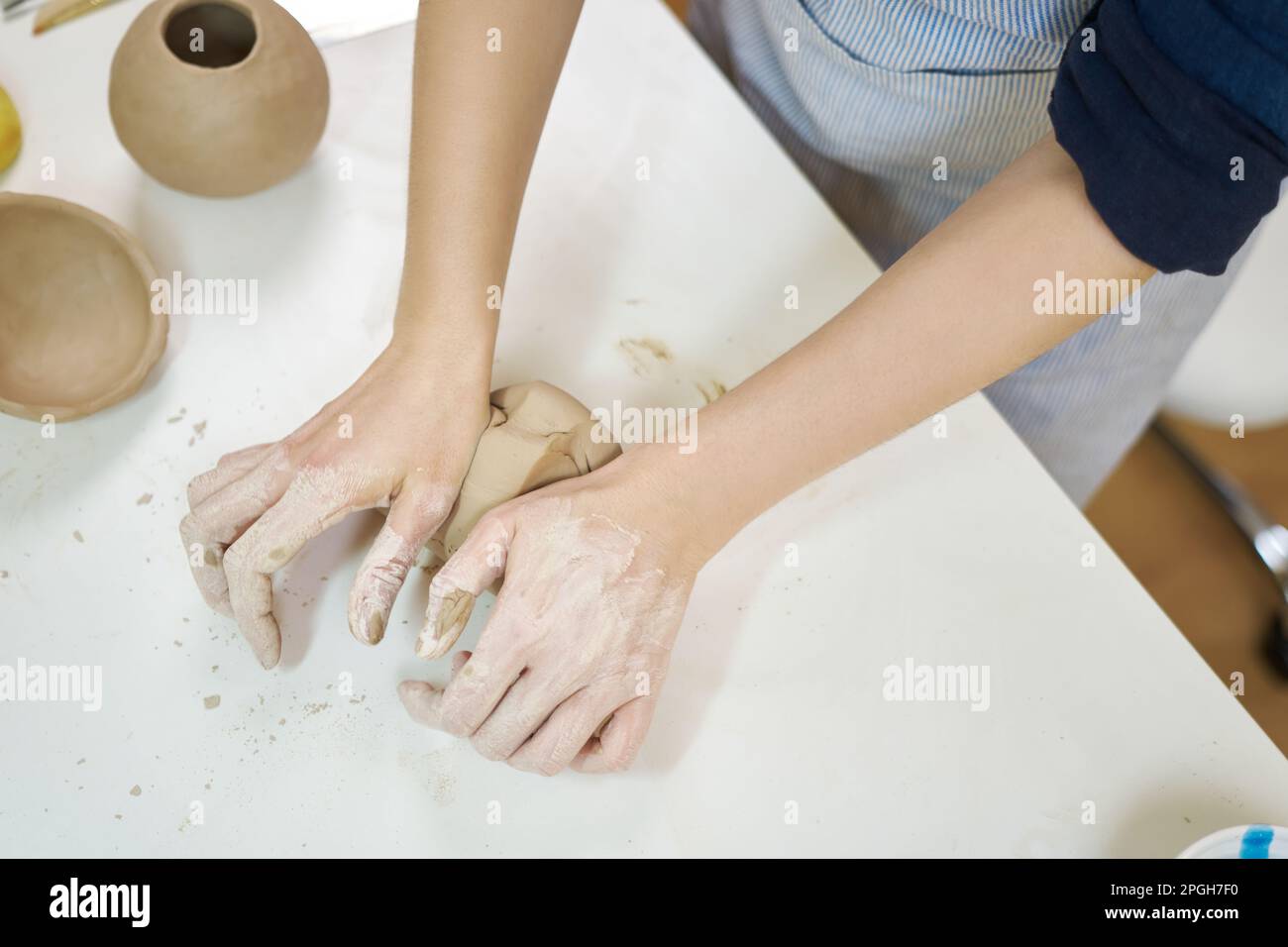 Closeup hands of ceramic artist wedging clay on a desk in art studio ...