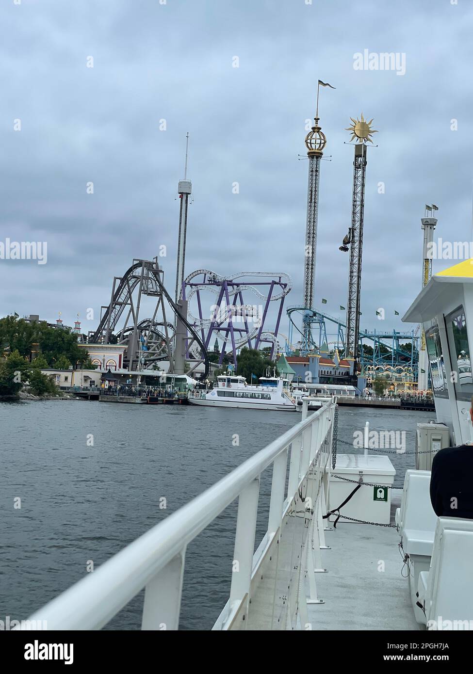 A small vessel sailing down the tranquil river with a modern amusement ...
