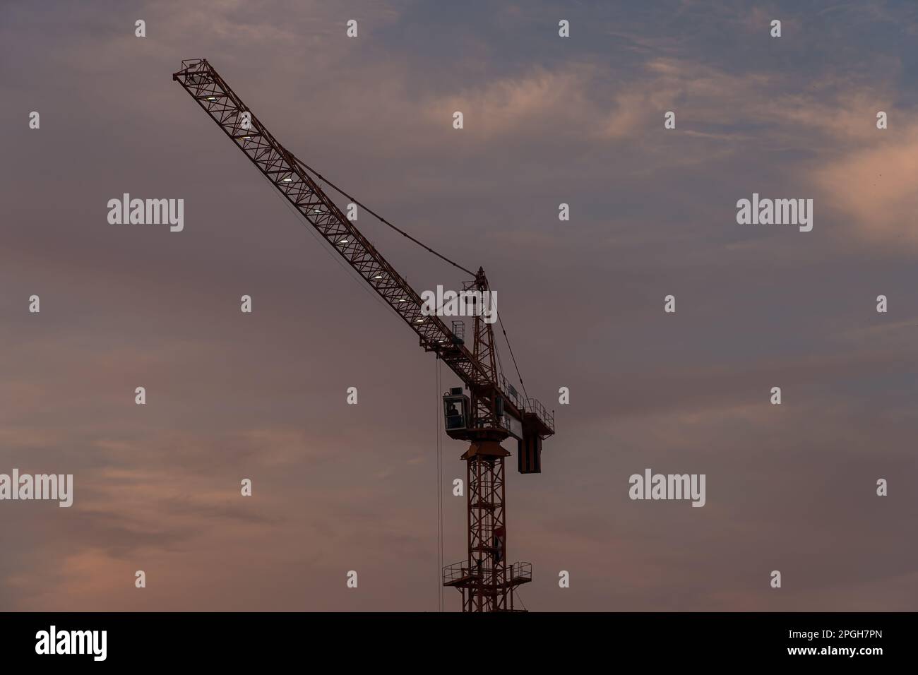 silhouette of a tower crane at a construction site at dusk with ...