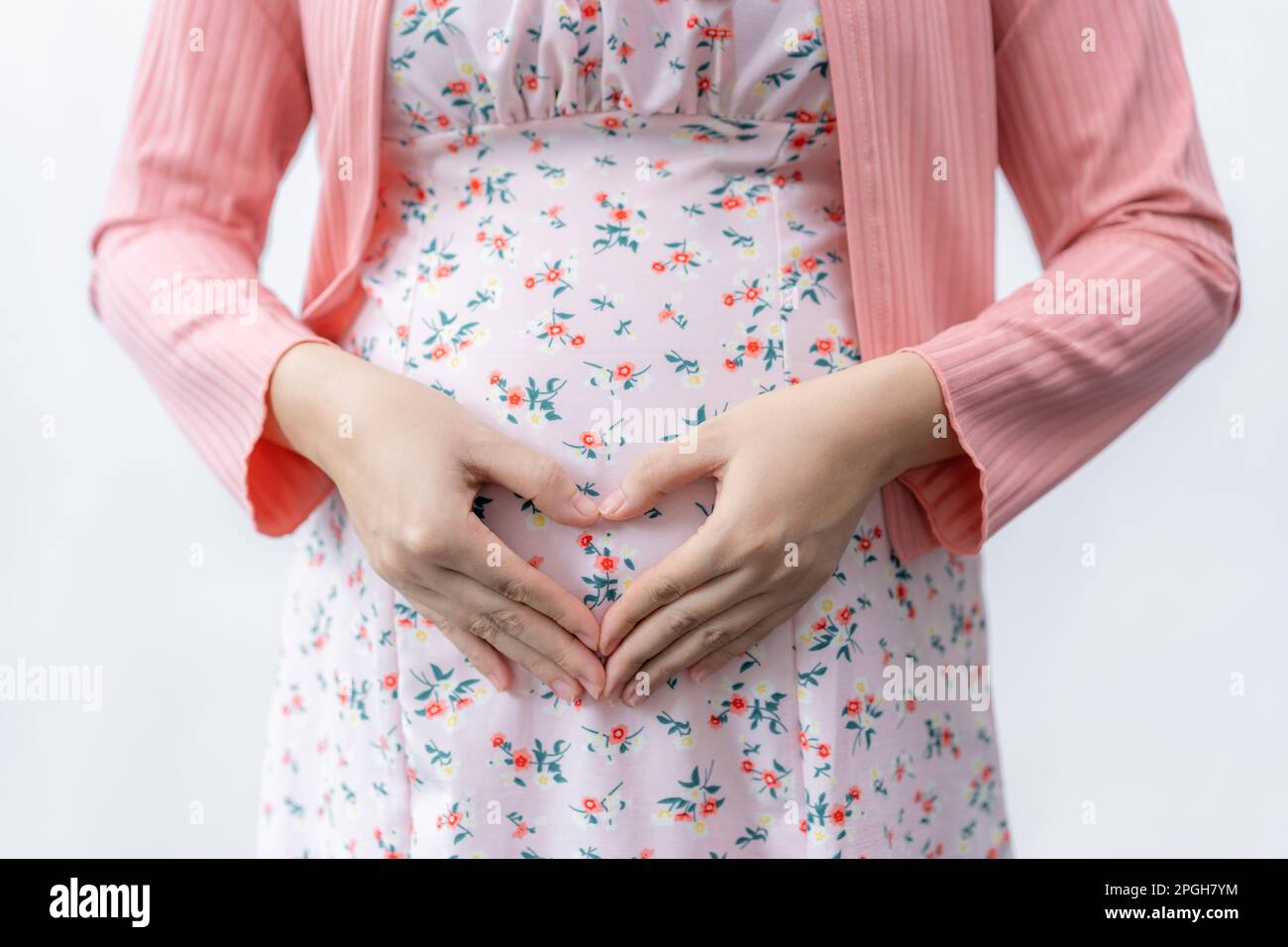 Prangnant woman in maternity dress putting her hands in heart shape ...