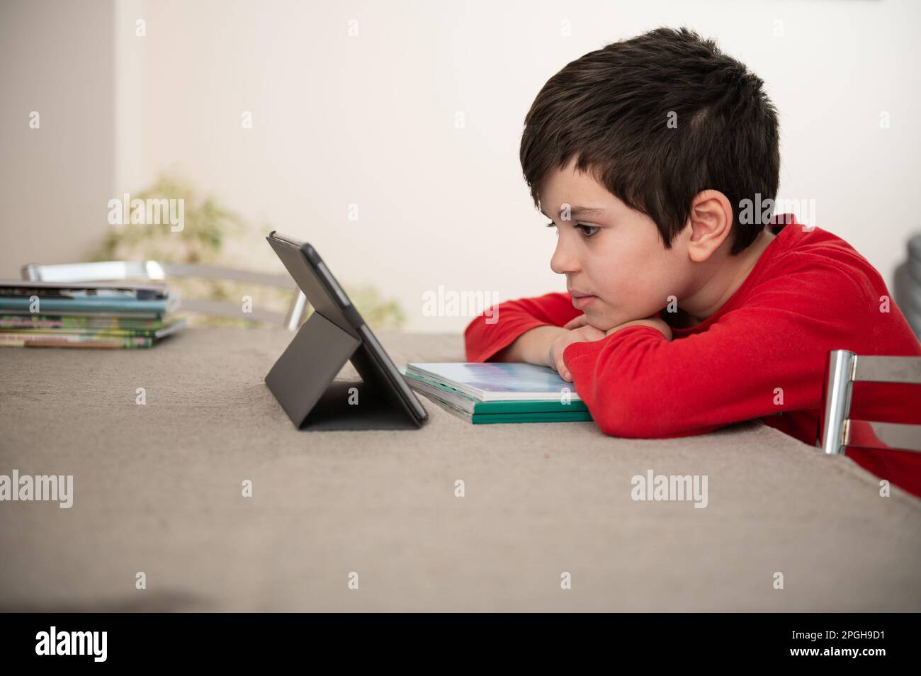 Elementary school student doing homework with digital tablet at home ...
