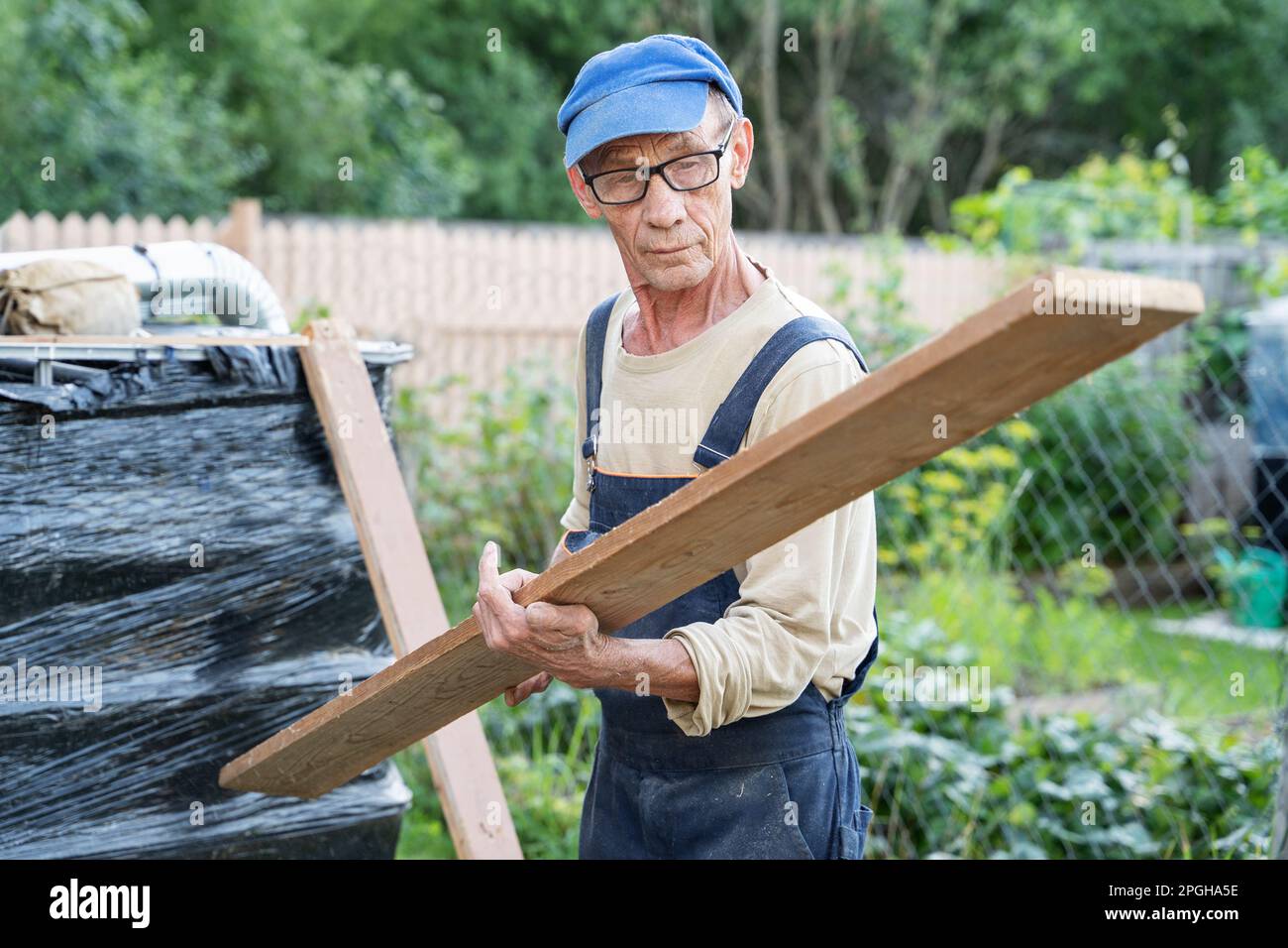 a carpenter processes wooden planks while on the street on a country ...