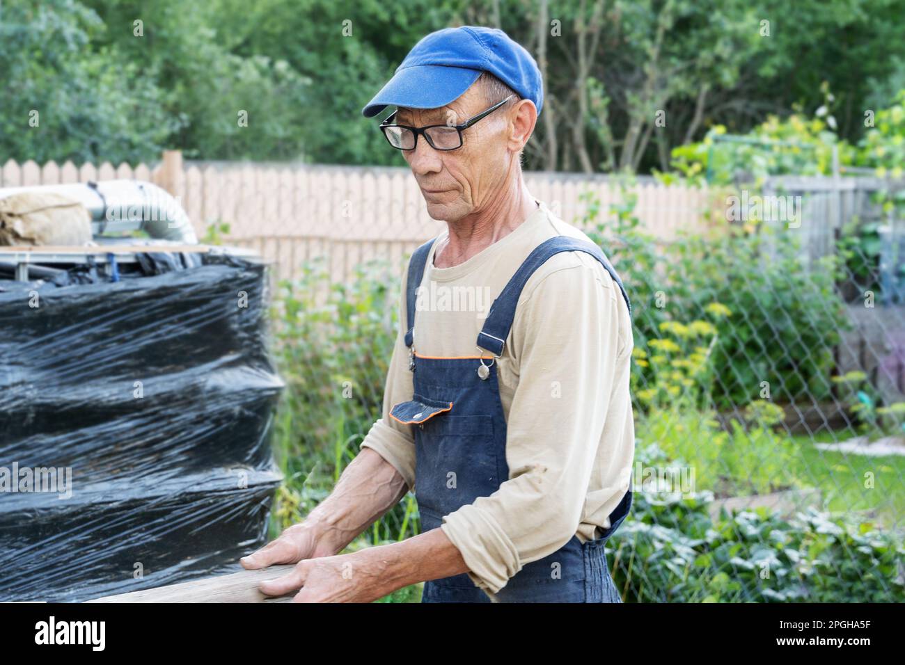 carpenter processes wooden planks while on the street on a country plot ...