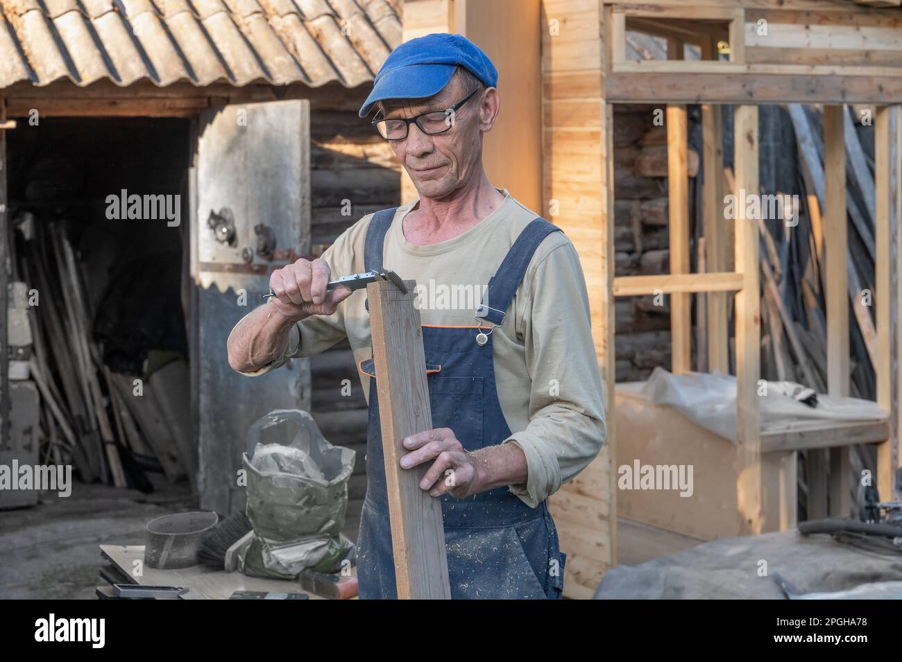 carpenter processes wooden planks while on the street on a country plot ...