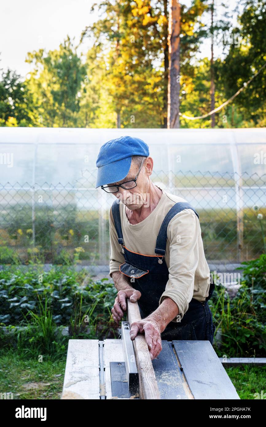 a carpenter processes wooden planks while on the street on a country ...
