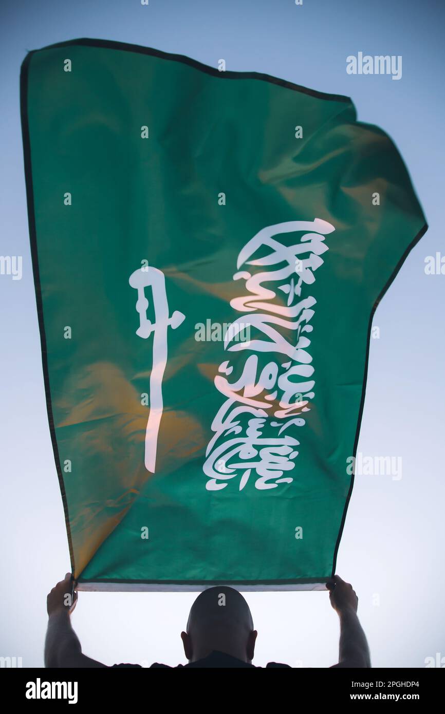 Saudi Arabia national flag waving in the hand of a man in sunset Stock ...