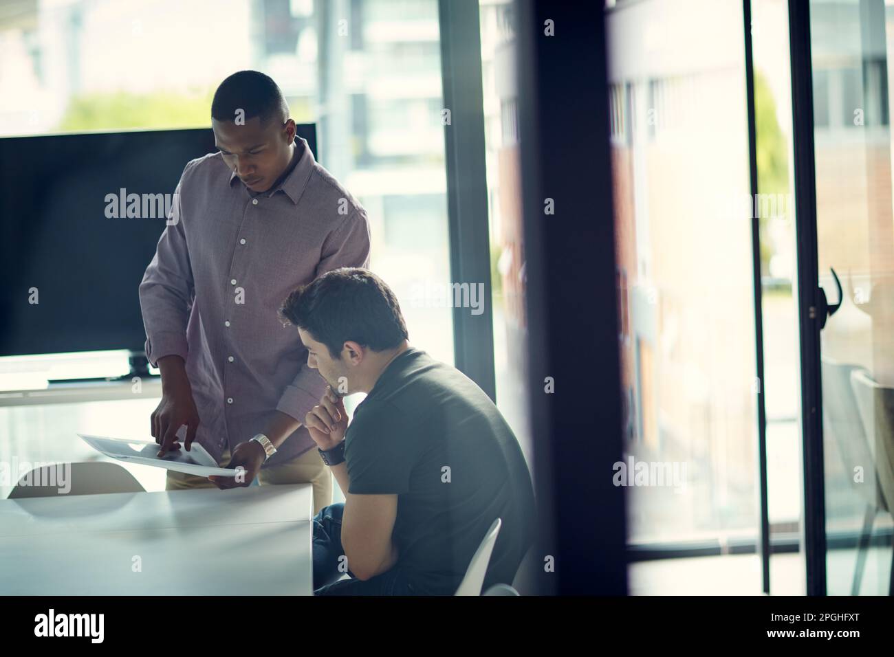 Taking a deeper look into business. two young businessmen going over ...