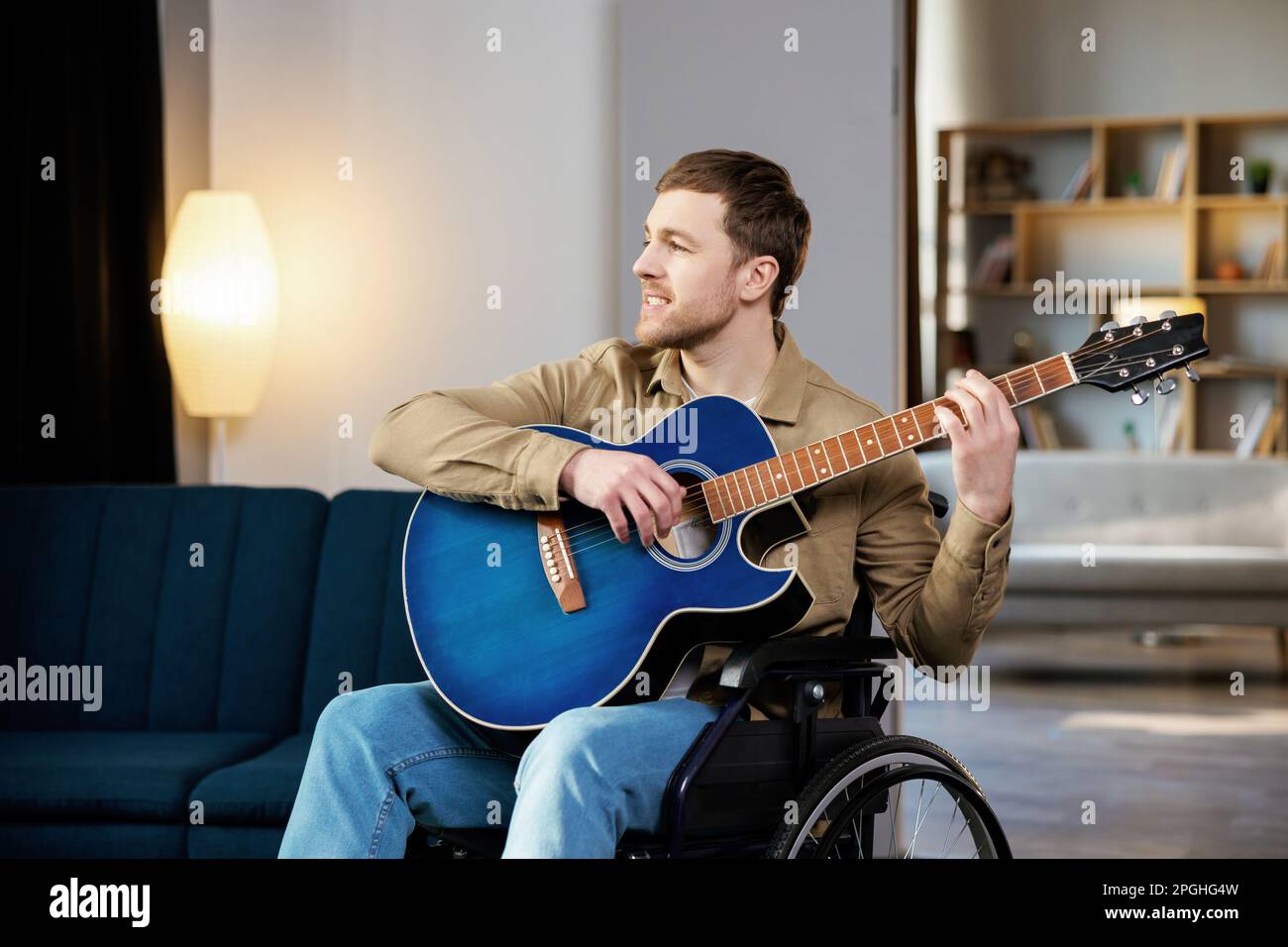 Handsome man with a disability sitting in wheelchair playing on guitar ...