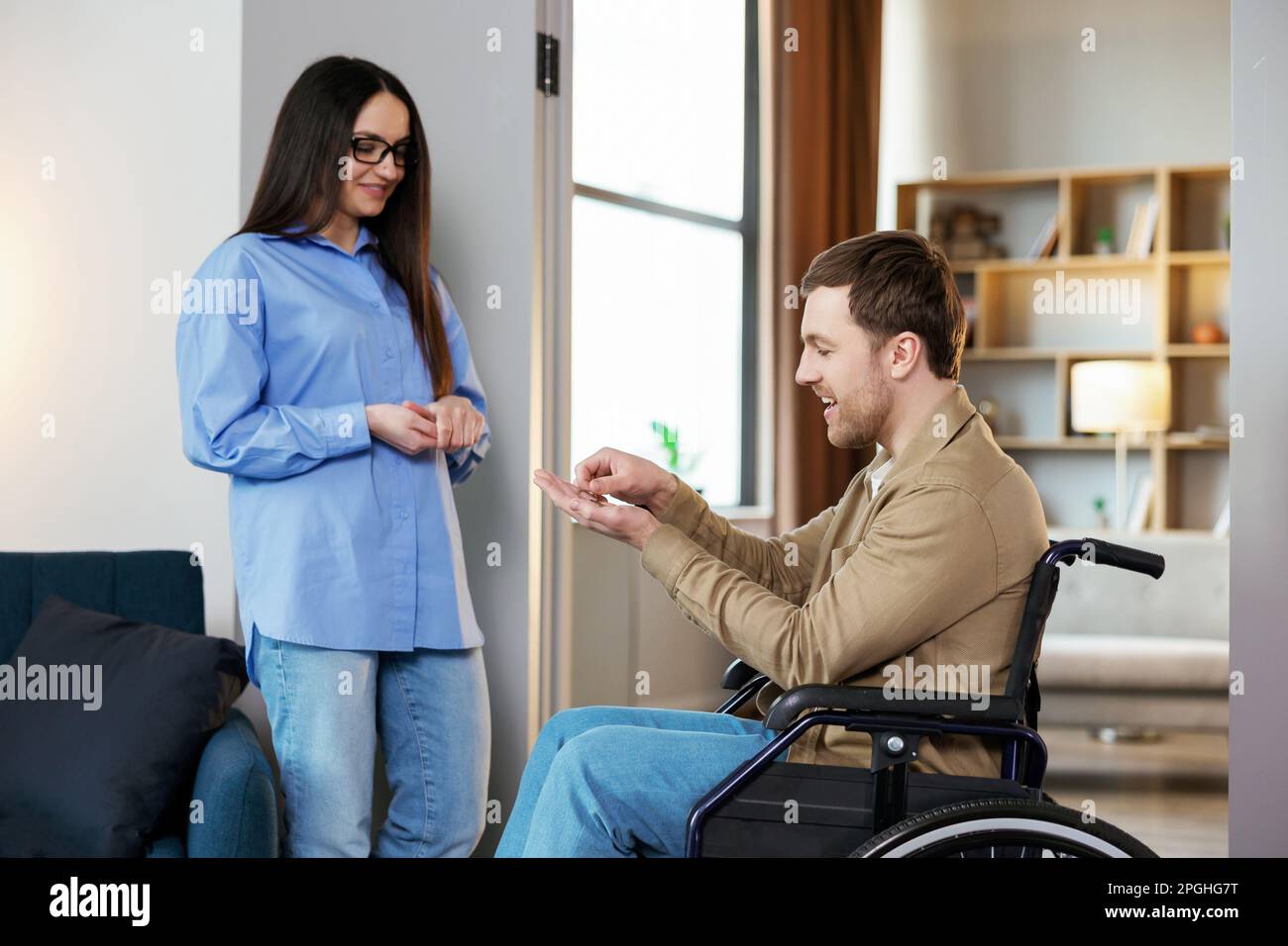 Man in wheelchair extend her hand palm up to side. Woman giving key ...