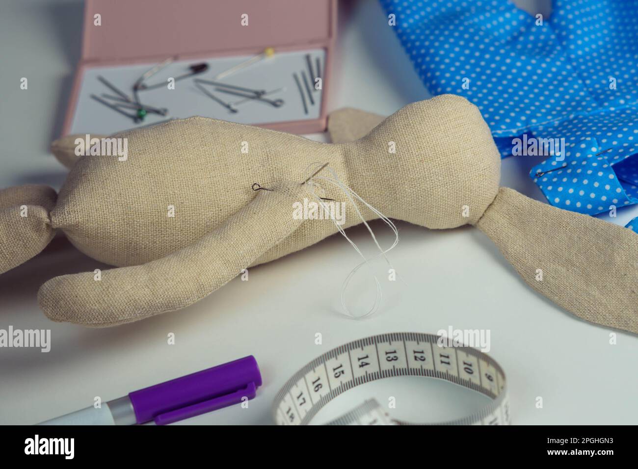 Sewing process of stuffed rabbit toy with needles in body lying on ...