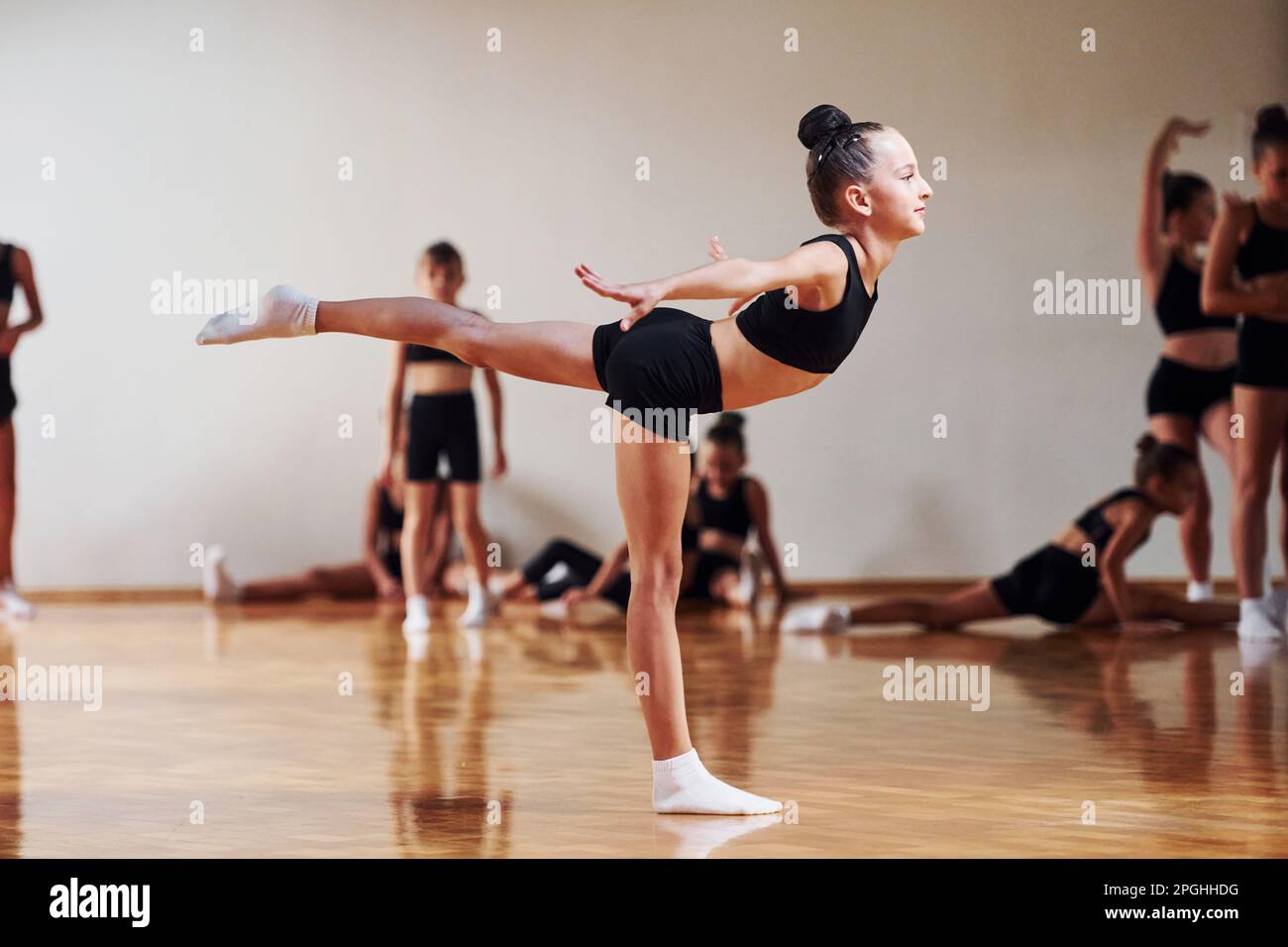Group of female kids practicing athletic exercises together indoors ...