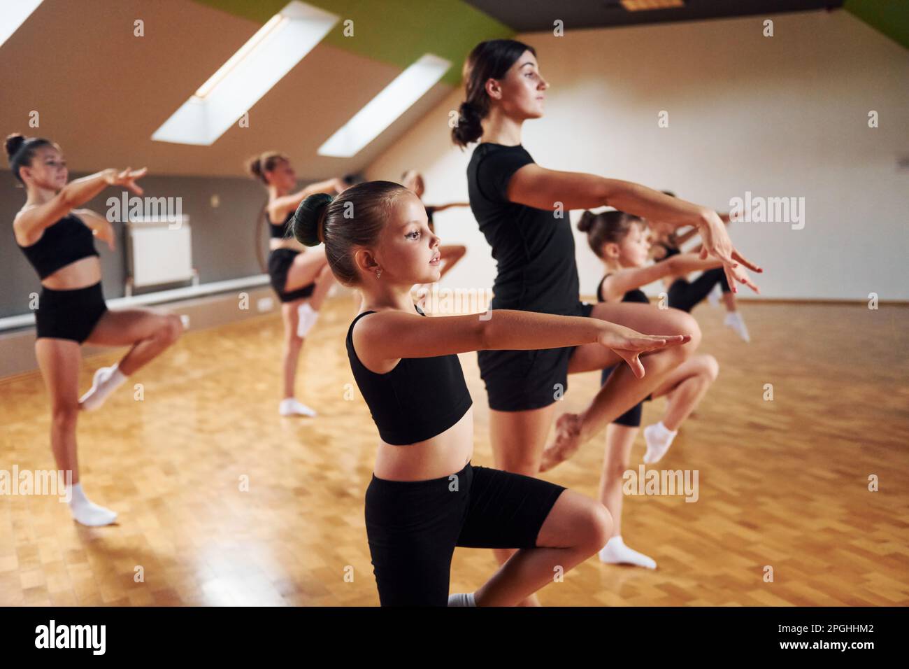 Learning from coach. Group of female kids practicing athletic exercises ...