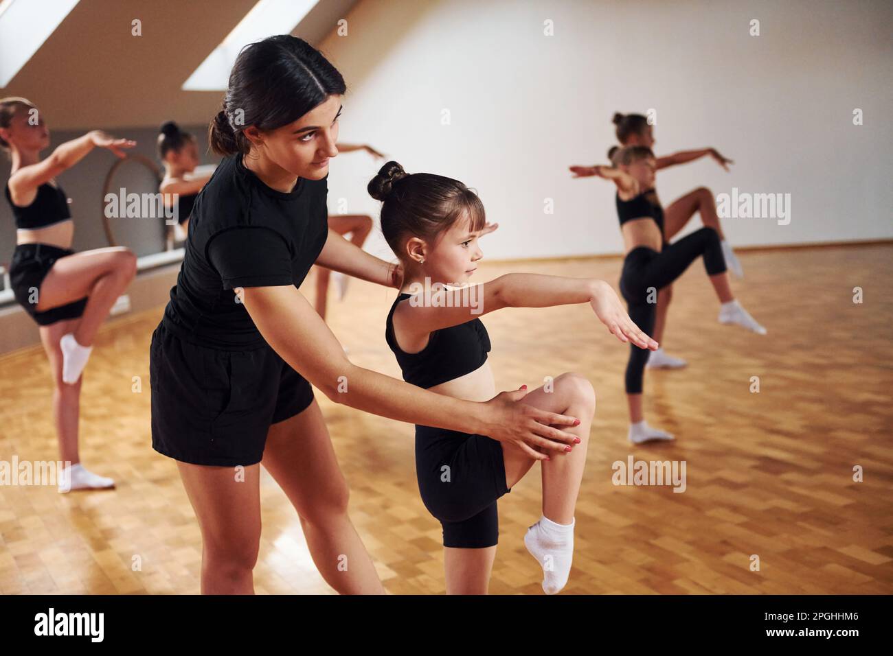 Learning from coach. Group of female kids practicing athletic exercises ...