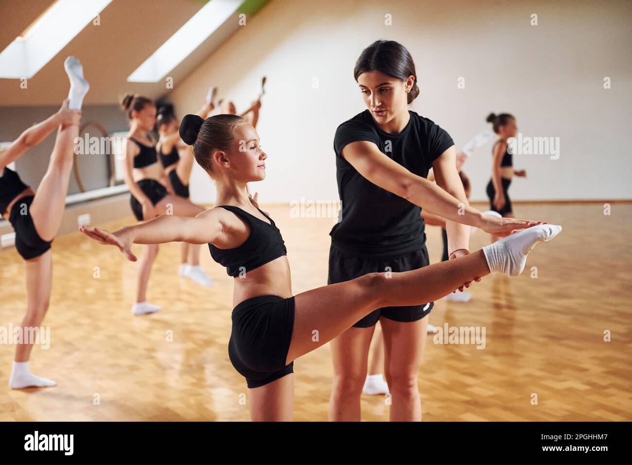 Learning from coach. Group of female kids practicing athletic exercises ...