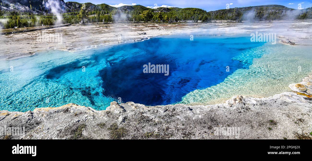 A picturesque view of a large hot spring pool, with vibrant blue water ...