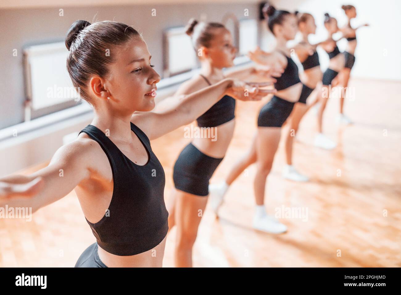Standing in the row. Group of female kids practicing athletic exercises ...