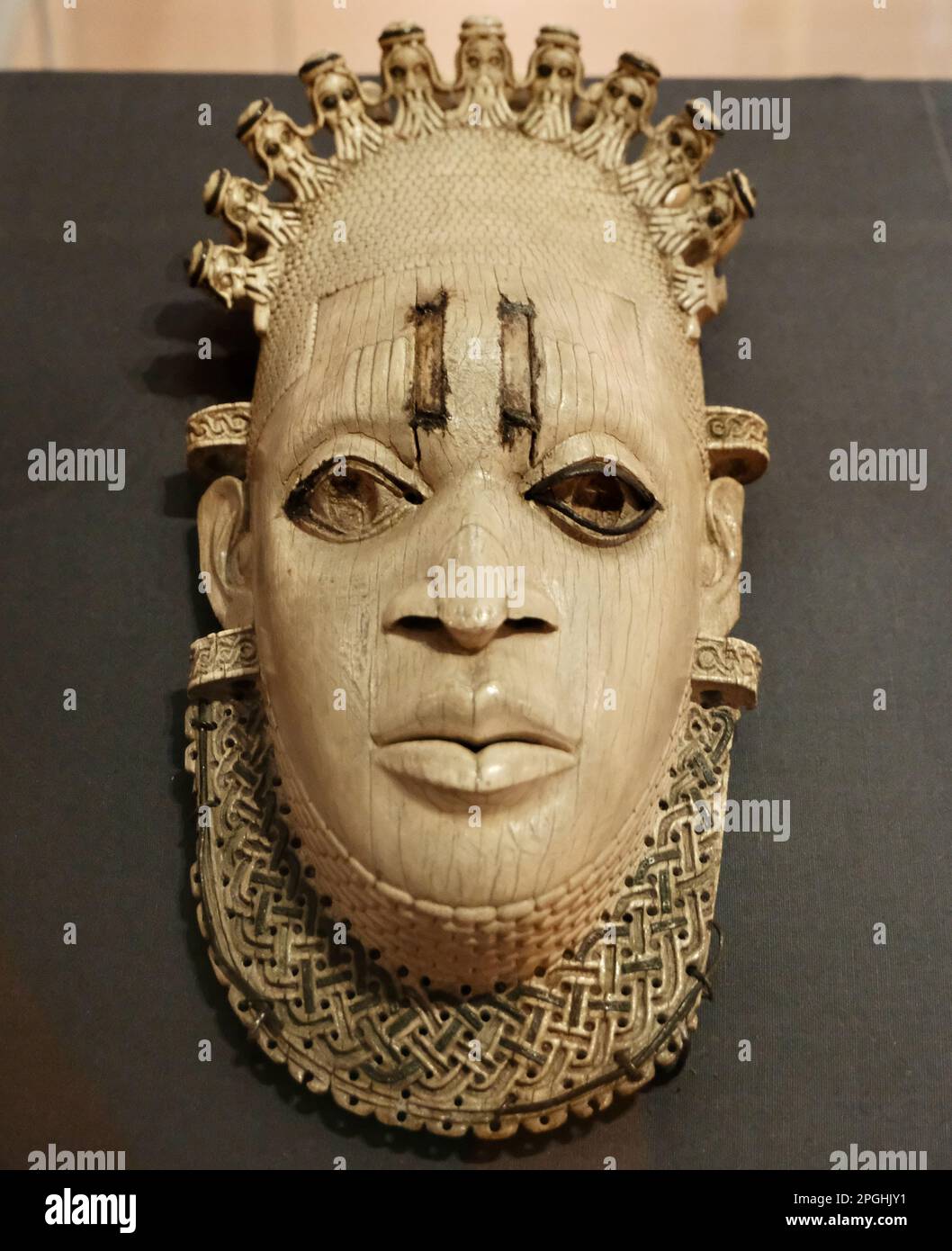 A closeup of a Benin ivory mask, featuring intricate designs and ...