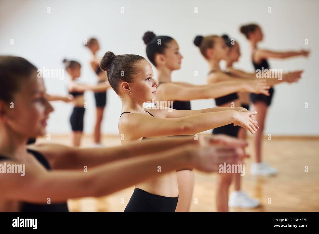 Side view of group of female kids that practicing athletic exercises ...