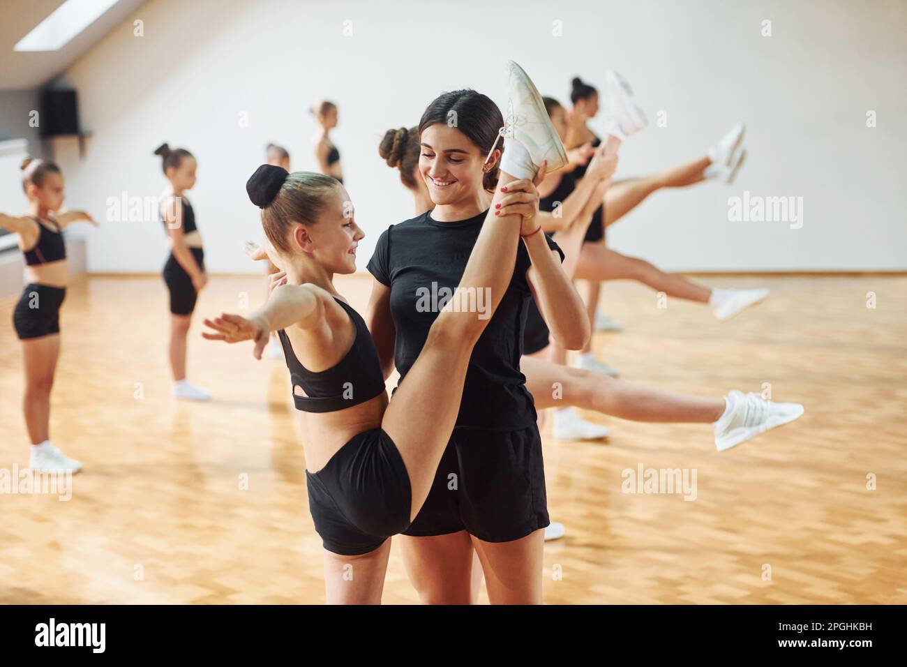 Learning from coach. Group of female kids practicing athletic exercises ...